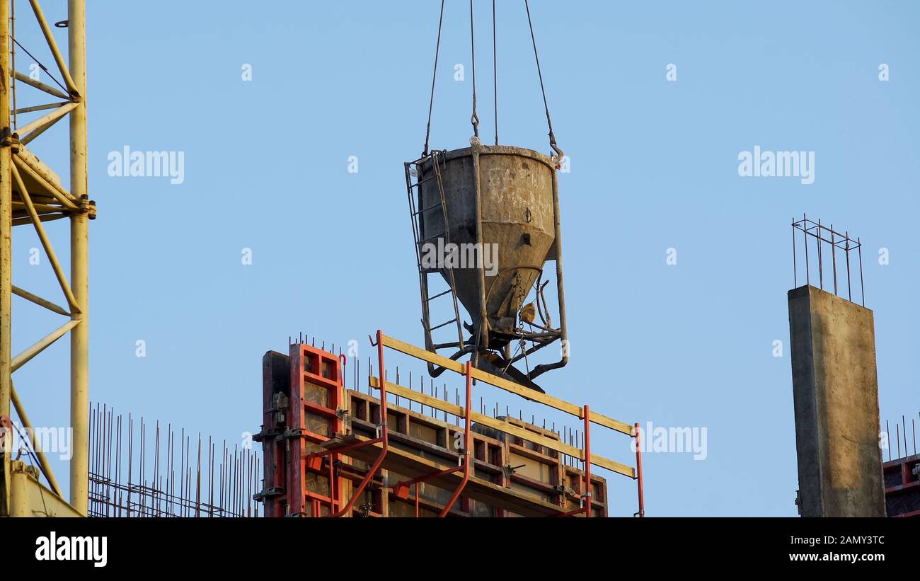 Container with concrete delivered by crane on building site ...