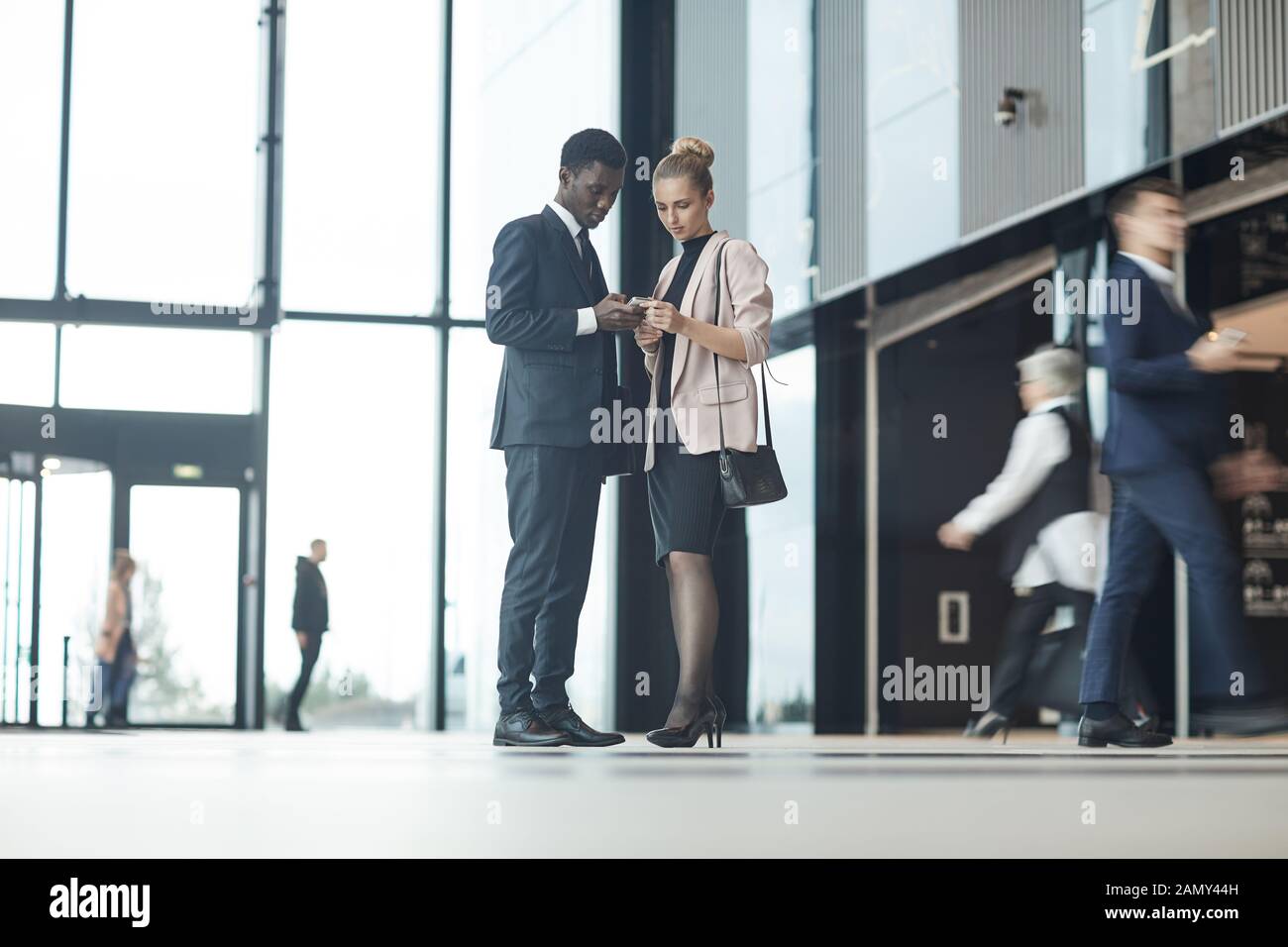 Two business partners using their mobile phones while standing in the ...