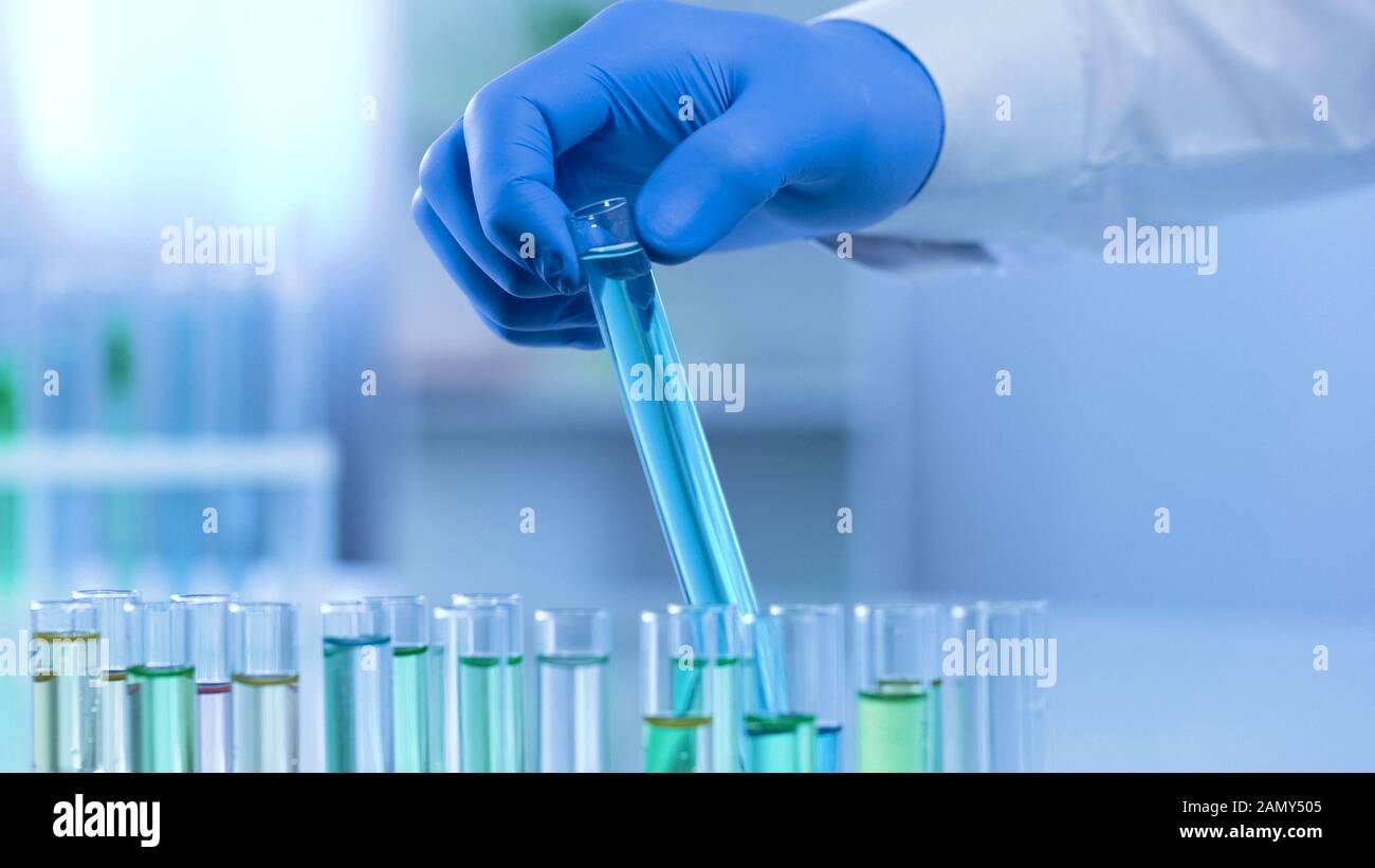 Assistant checking blue substance in test tube, laundry detergent ...