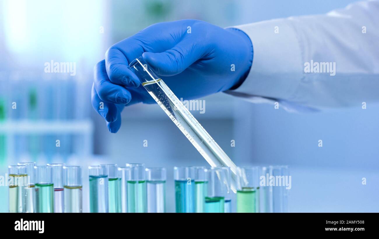 Lab worker taking test tube watching changes in substance, scientific ...