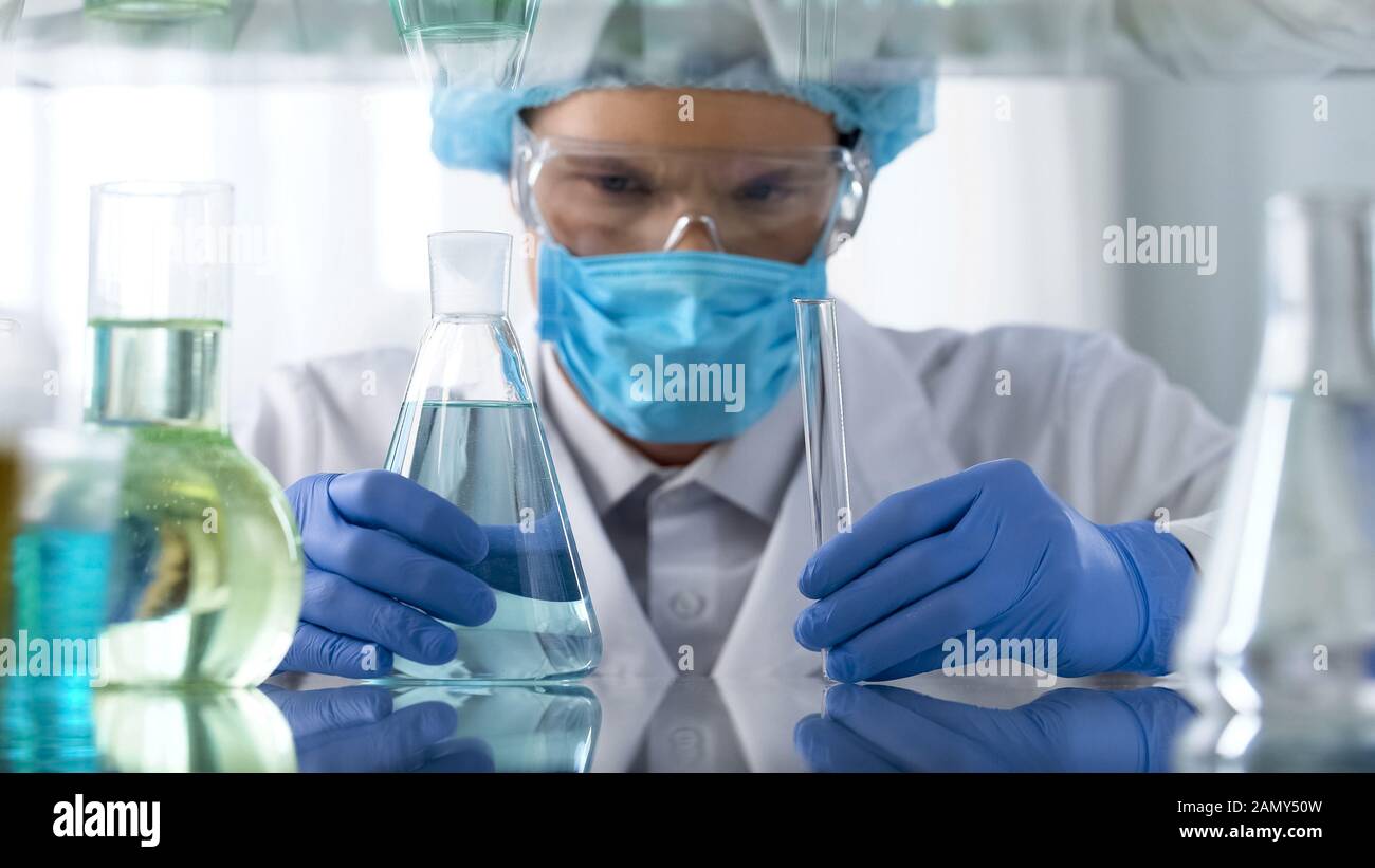Laboratory worker in special suit preparing reagents for scientific ...