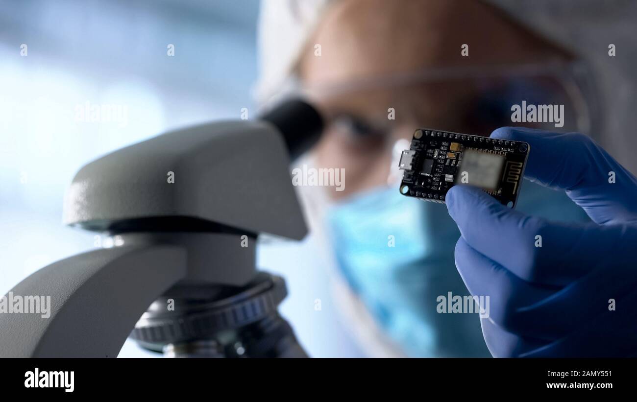 Technician examining chip, using microscope to run diagnosis and ...