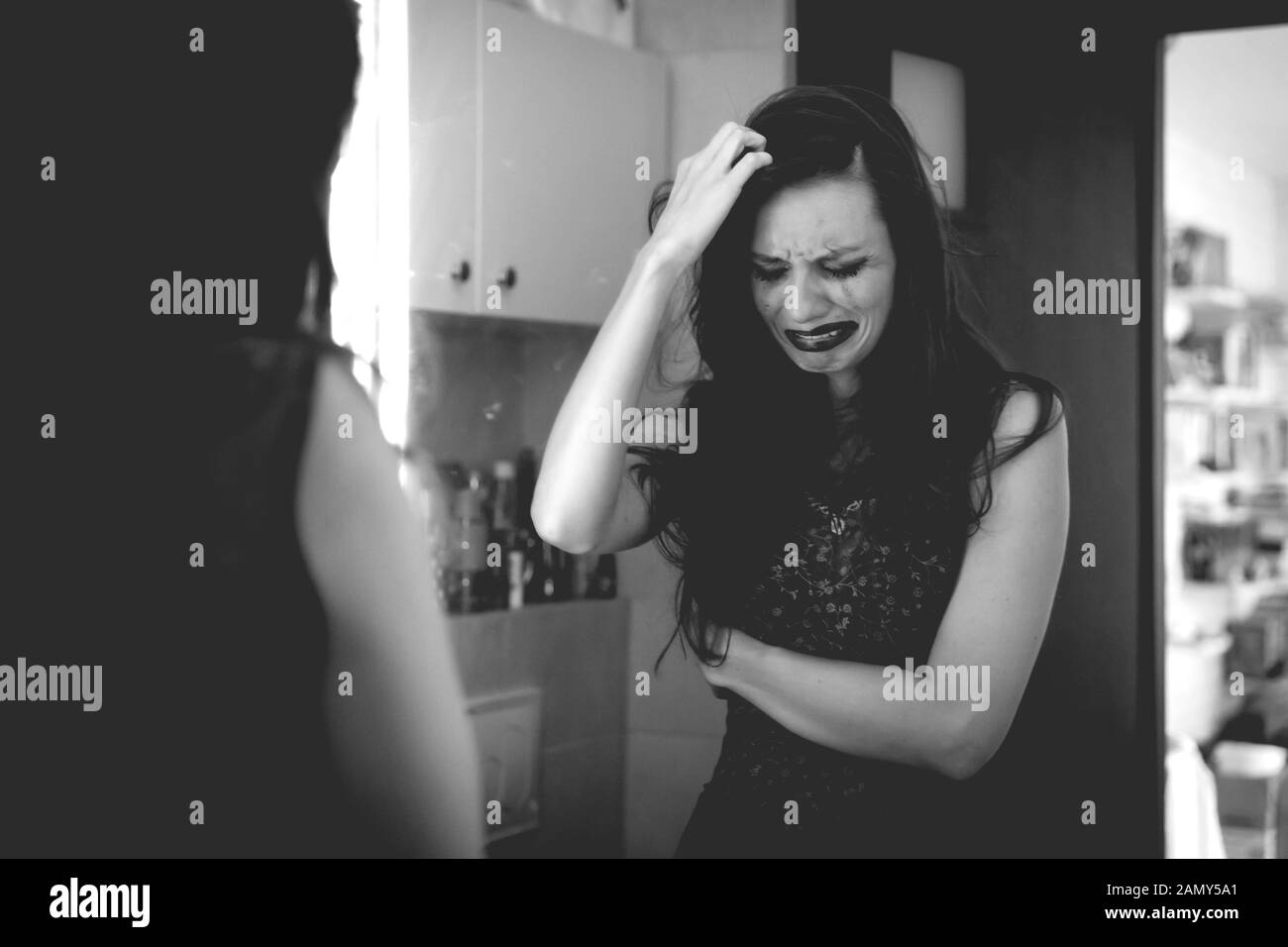 Woman standing in front of a mirror with exagerated lipstick on her ...