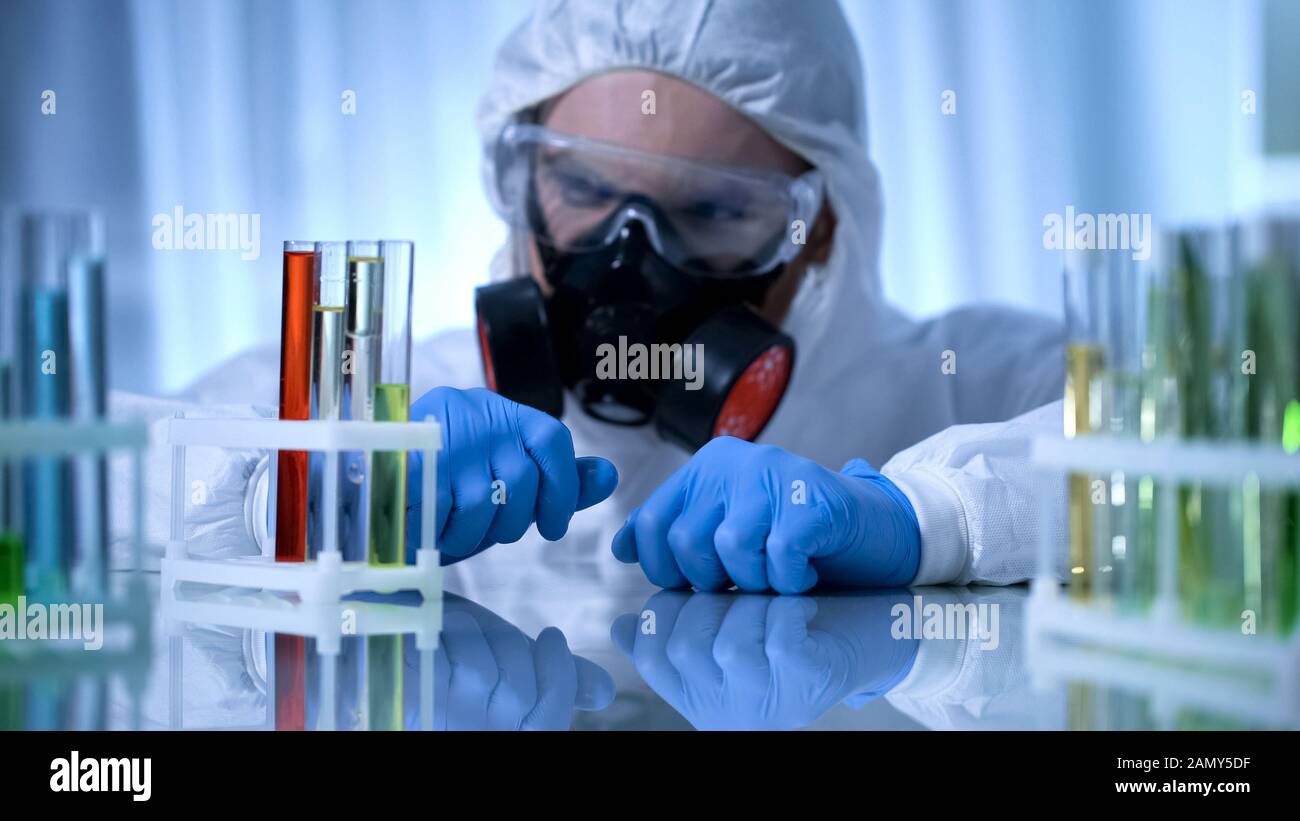 Male chemist checking test tubes with biohazard substance, toxicology ...