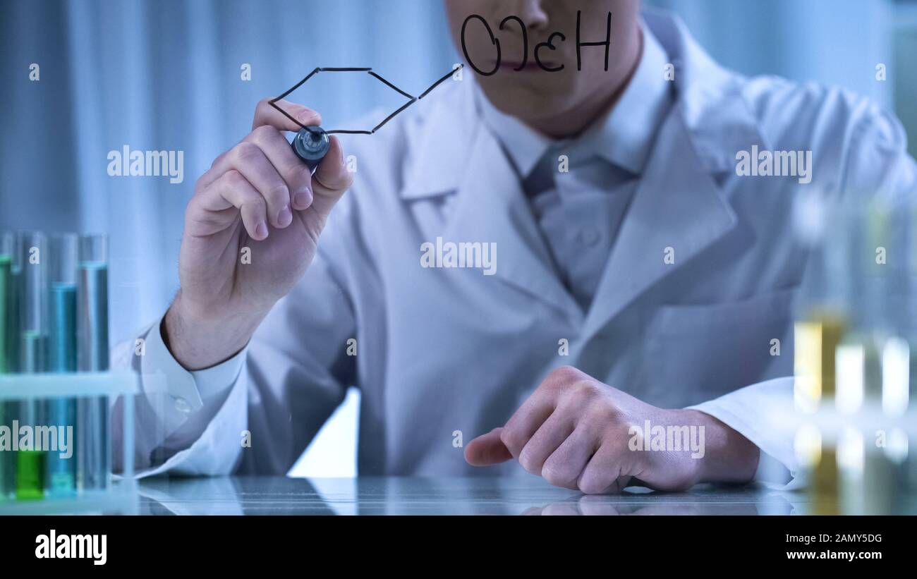 Scientist writing chemical formula on transparent board, pharmaceutical ...