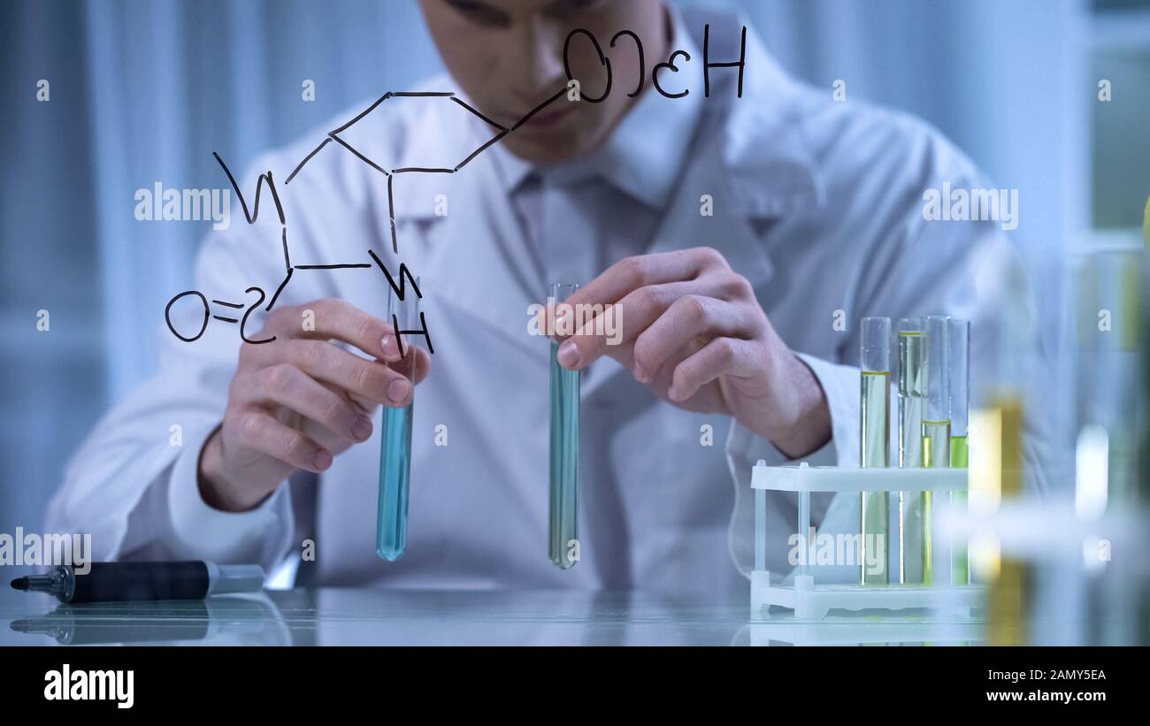 Researcher mixing reagents in test tubes according to formula written ...