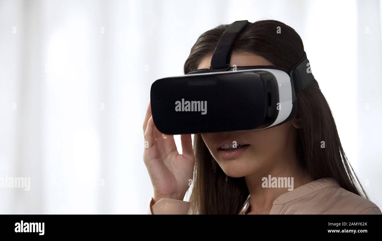 Pretty girl using futuristic VR technology and laughing, pleased with ...