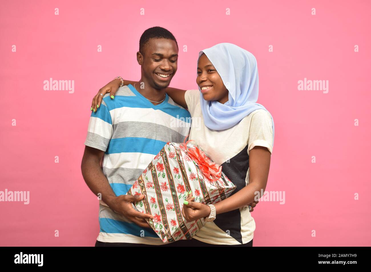 young black man gifting a wrapped present to a lady Stock Photo - Alamy