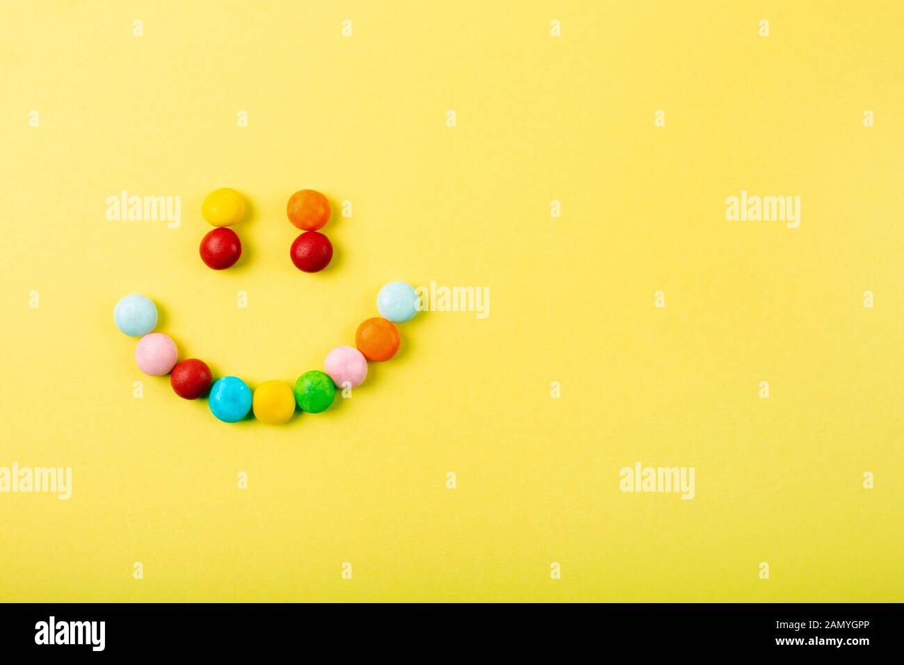 Mixed of colorful candies on yellow background. Smily face Stock Photo ...
