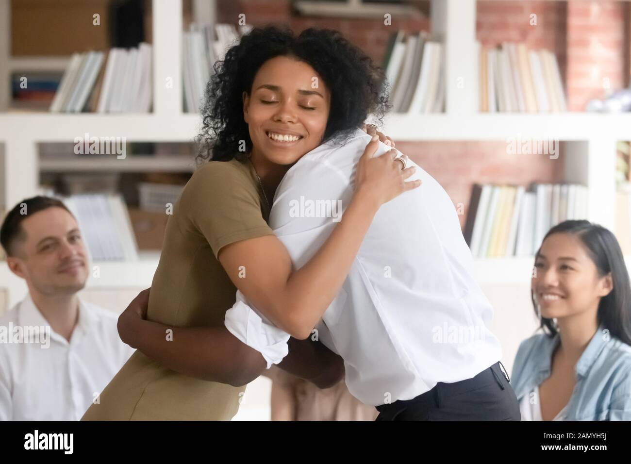 Diverse people hug show empathy at group counselling Stock Photo - Alamy