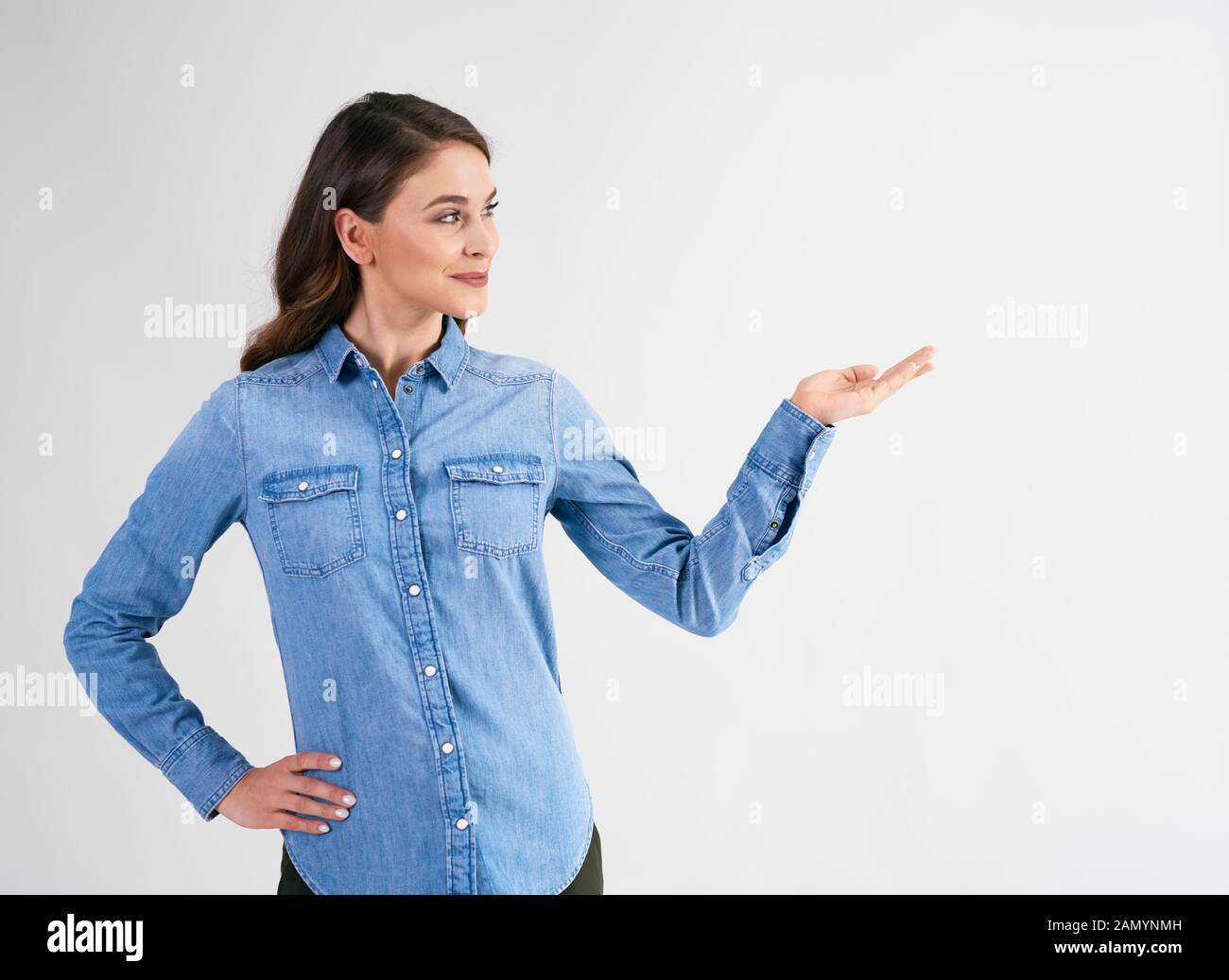 Smiling woman pointing at copy space at studio shot Stock Photo - Alamy