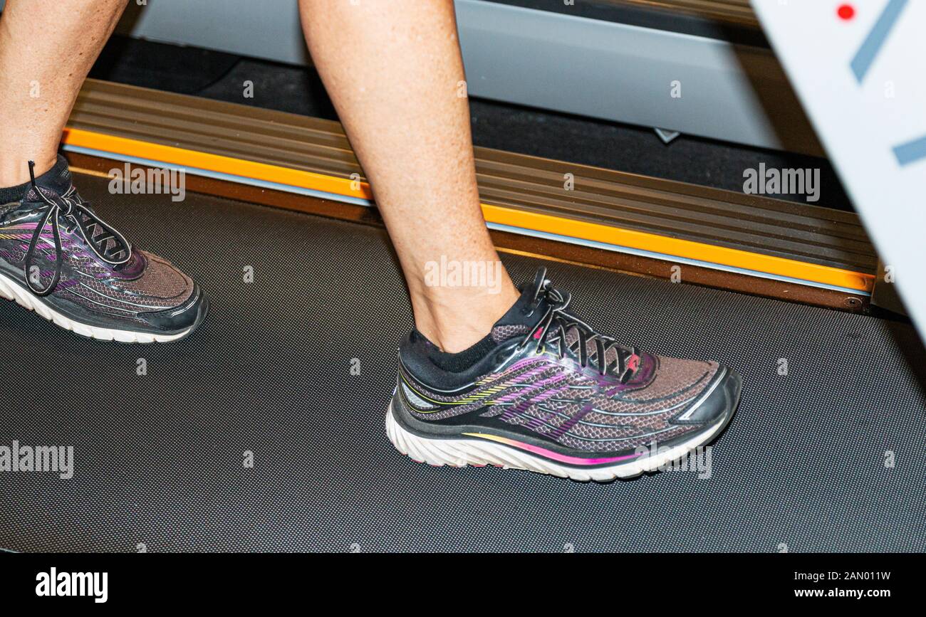 A persons feet are running and walking on a treadmill inside Stock ...