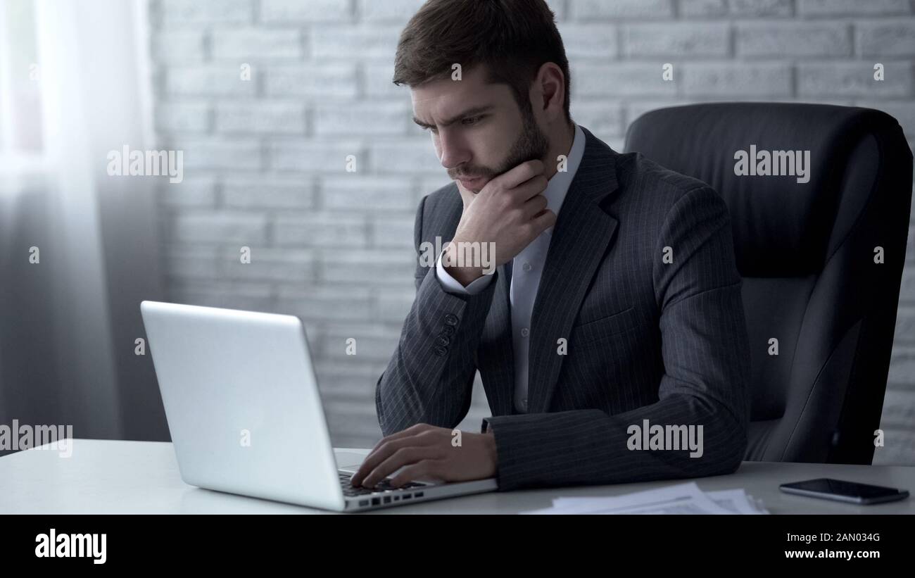 Pensive businessman typing on laptop, nervous about difficult startup ...