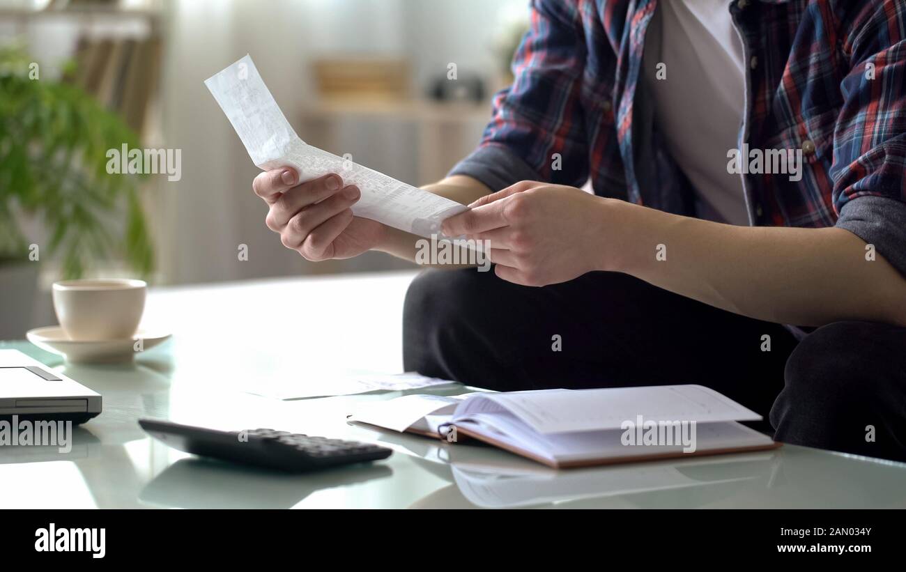 Man revising check for utilities, calculating income and expenses ...