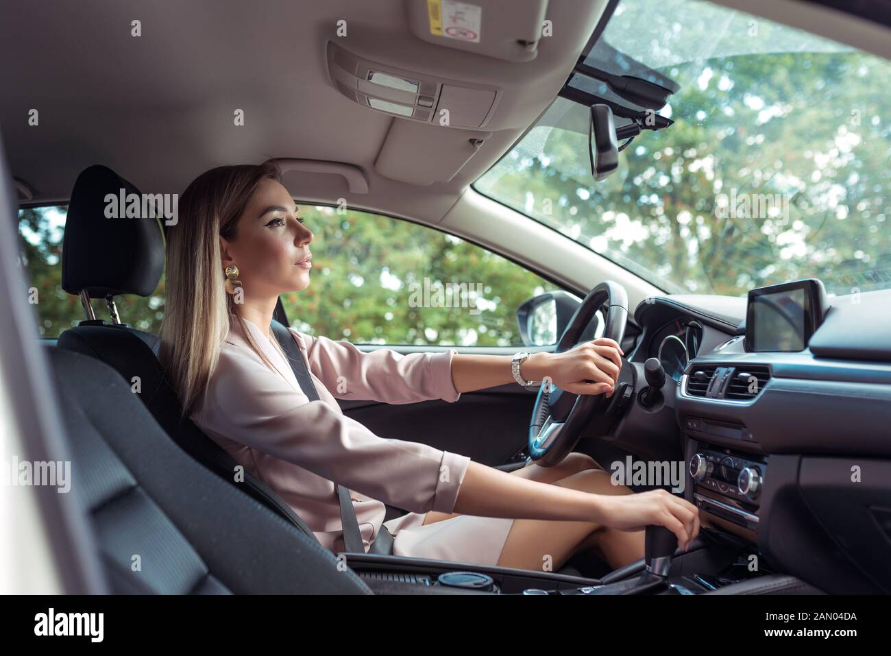 woman driving a car, in summer parking looks in rearview mirror ...