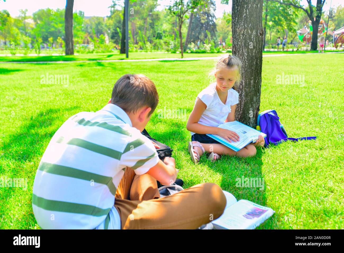 Children do homework in the park, a boy and a girl are preparing for ...