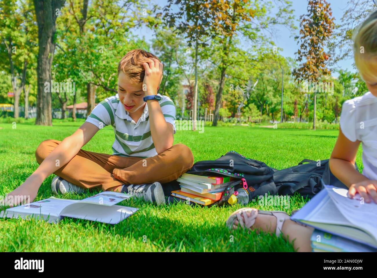 Children do homework in the park, a boy and a girl are preparing for ...
