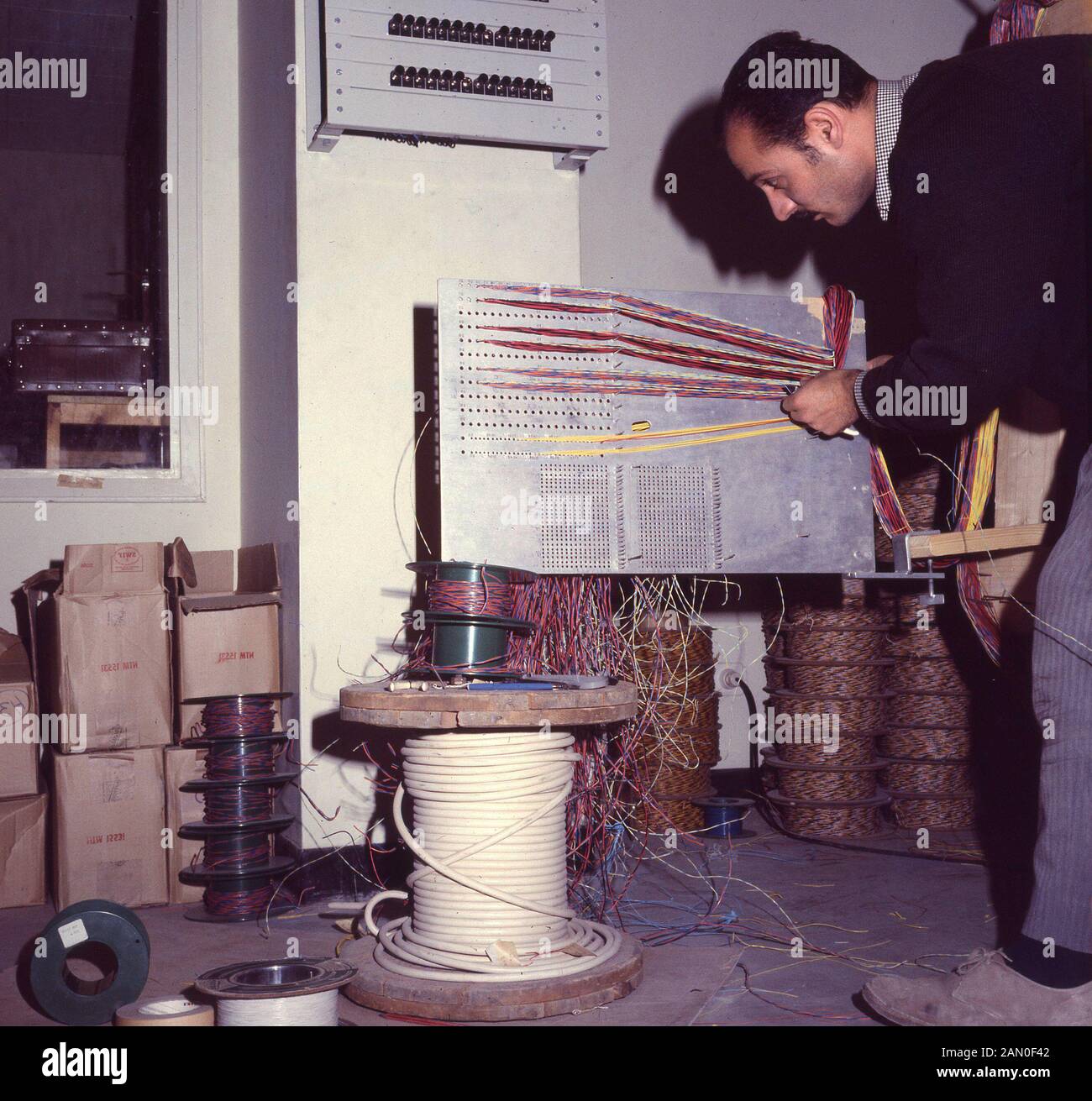 1960s, historical, a male electrician doing wiring or cabling ...