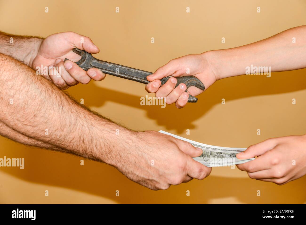 A wrench and money in the hands of people making a deal Stock Photo - Alamy