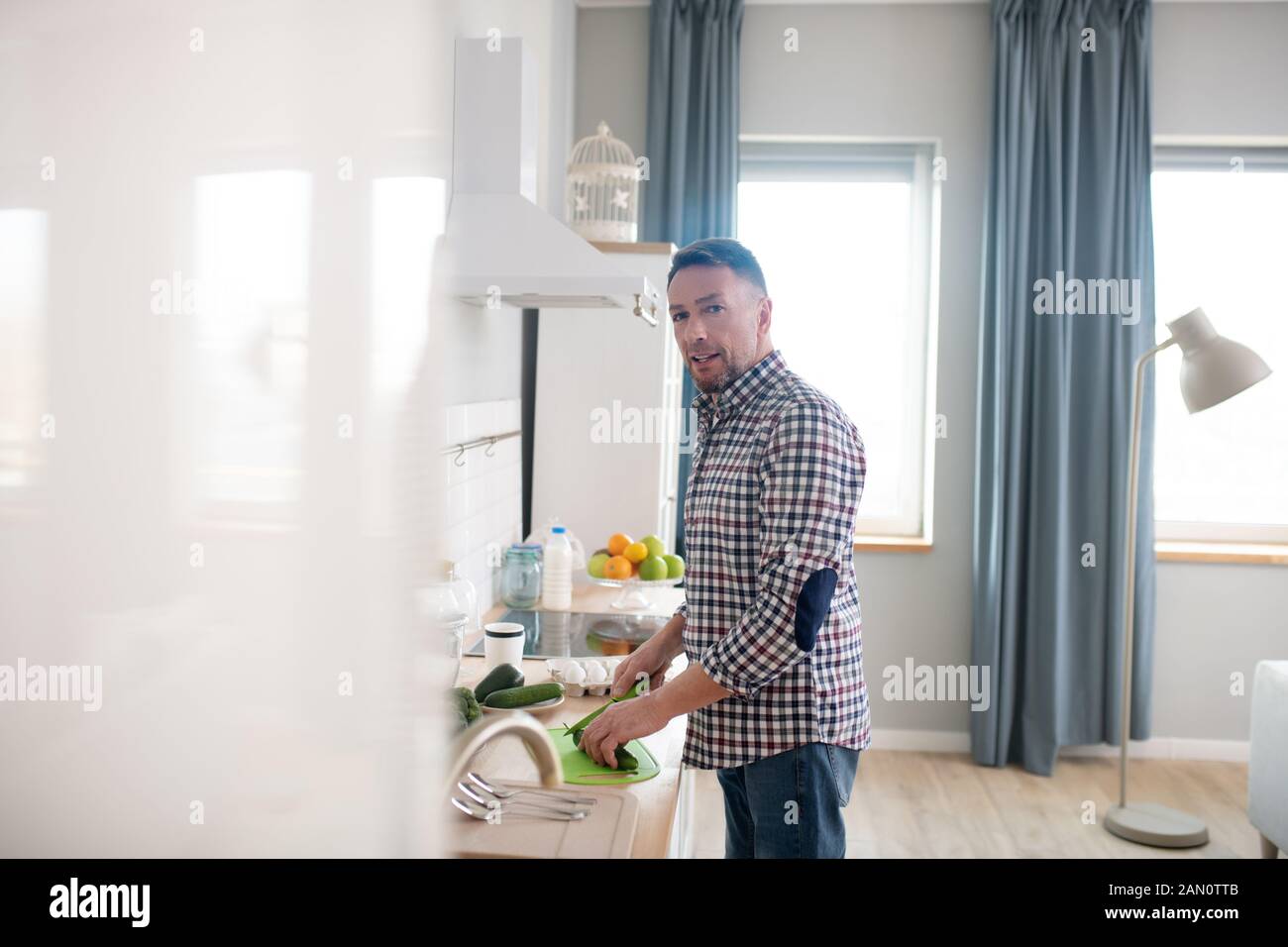 Man in a checkered shirt cooking in the kitchen Stock Photo - Alamy
