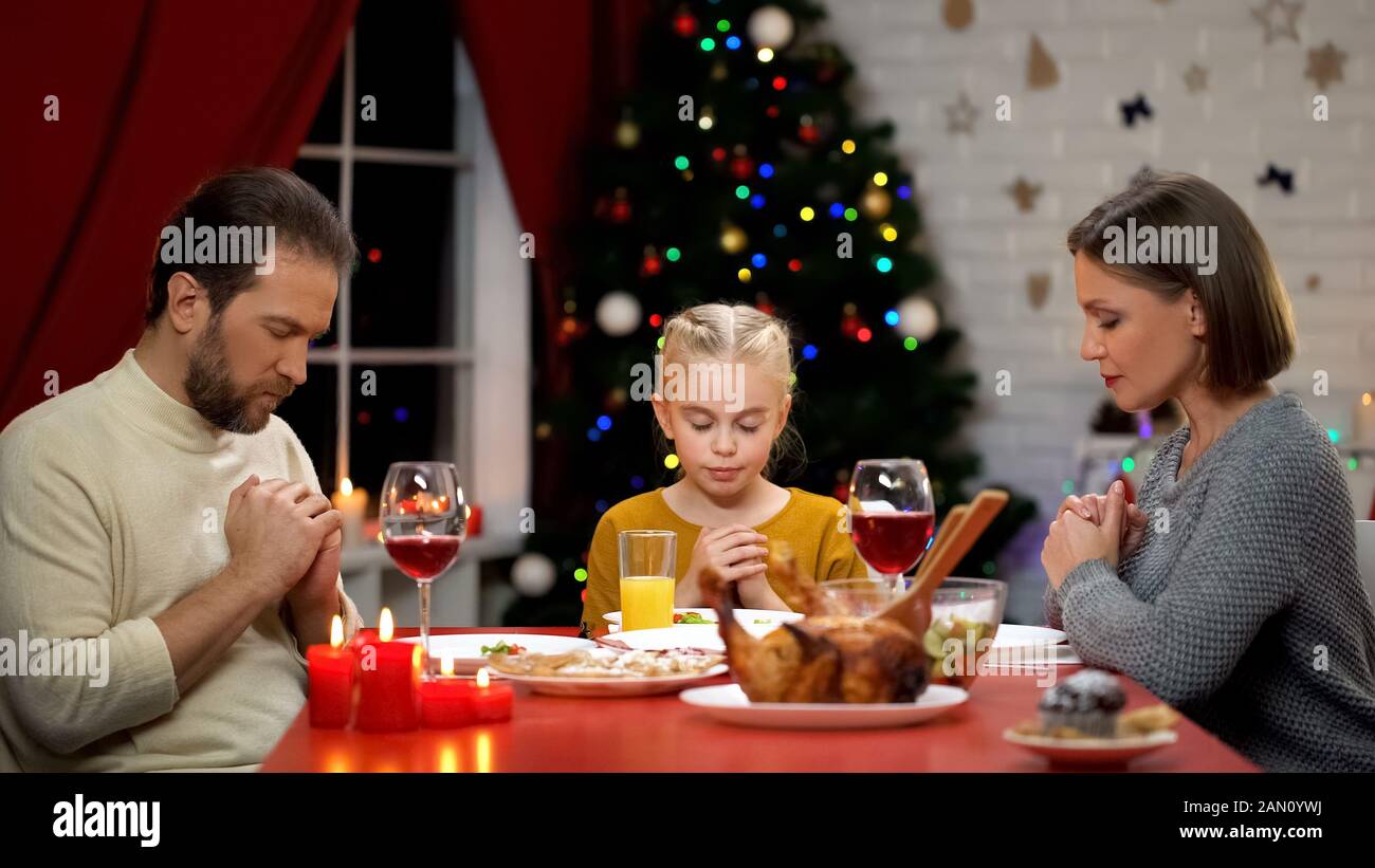 Traditional family praying before Xmas dinner, belief in god ...