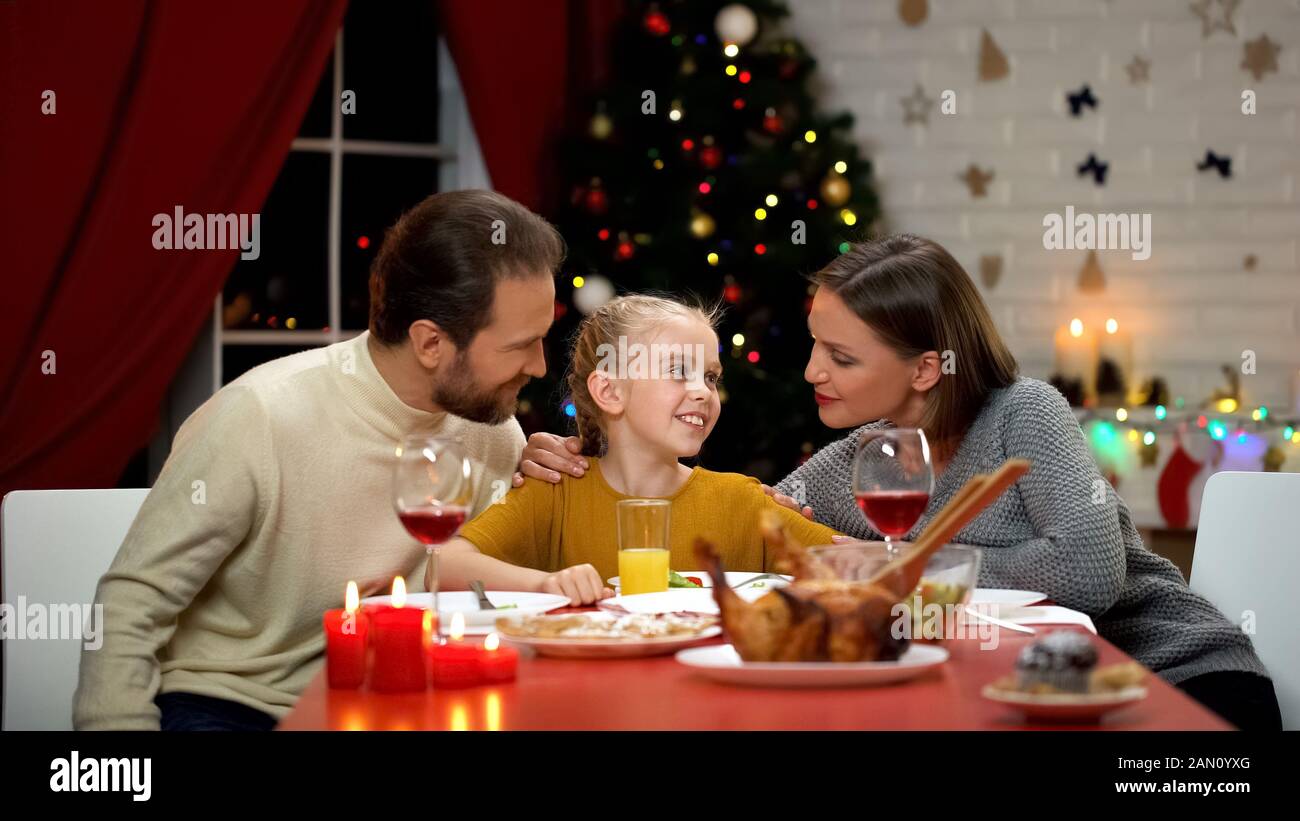 Parents hugging daughter at Xmas lunch, happy family celebrating ...