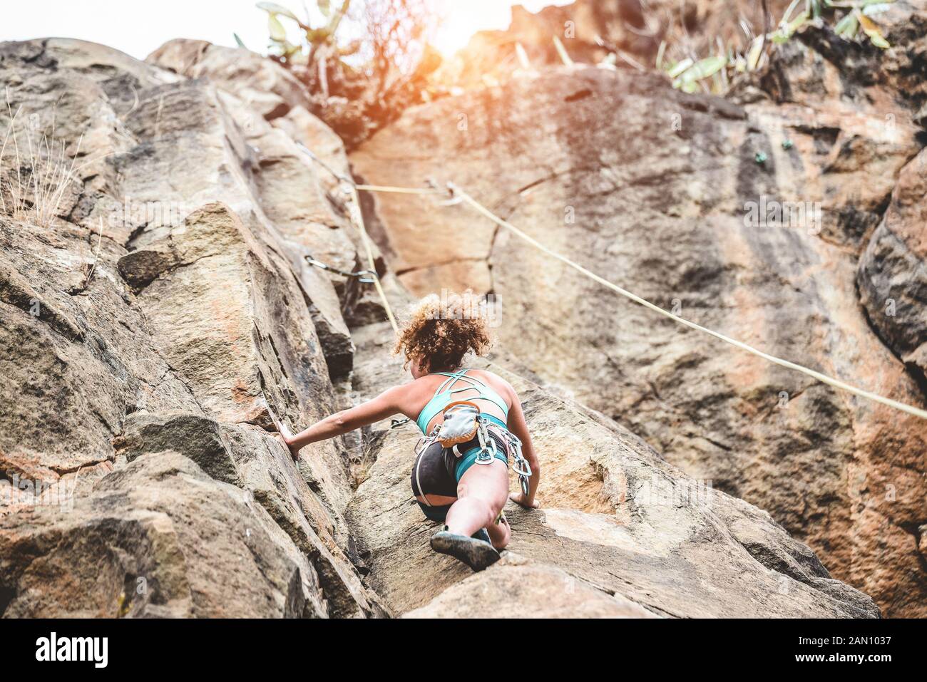 Young woman climbing a rock wall in a canyon - Strong climber training ...