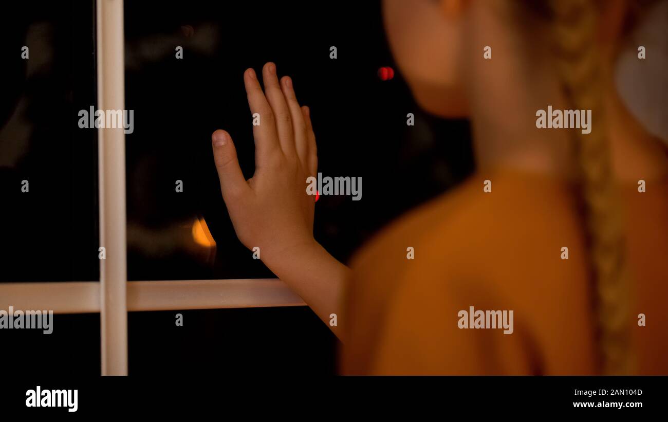 Sad lonely girl looking through window, waiting parents in orphan home ...