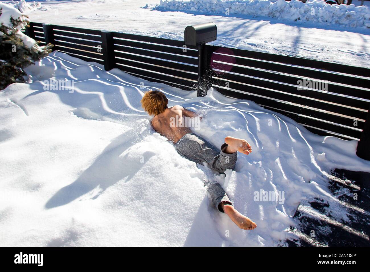 Teenage boy jumping into snow with no shirt Stock Photo - Alamy