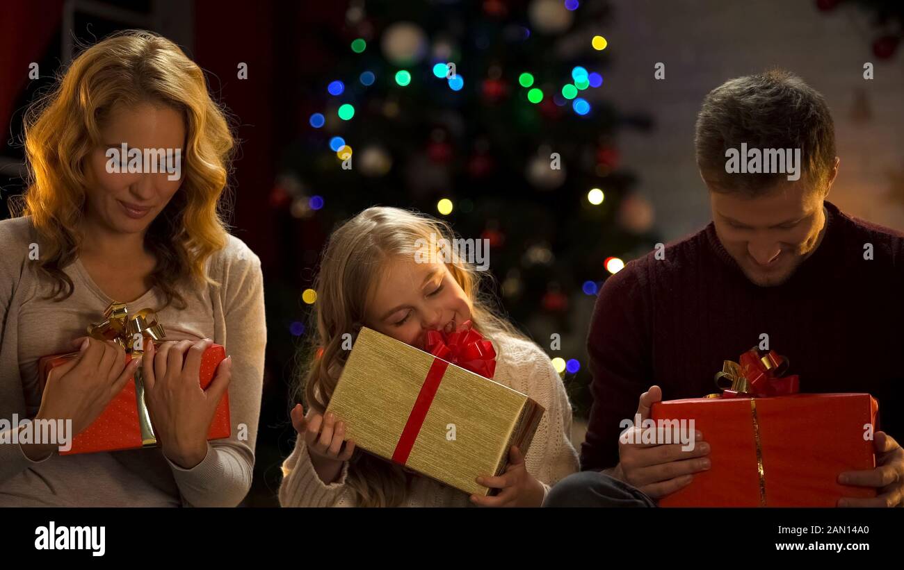 Excited family receiving Christmas presents, hugging boxes, dreams come ...
