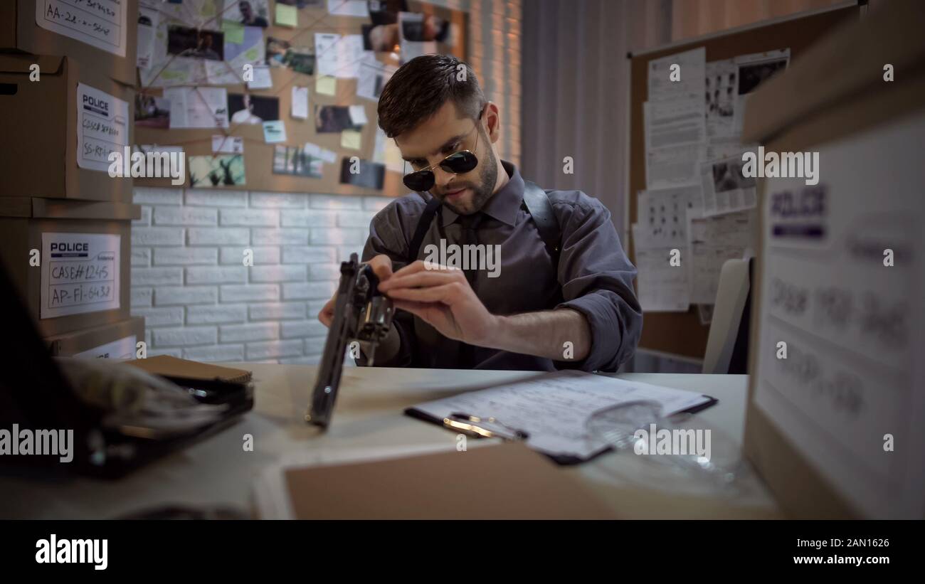 Policeman in office charging the gun on table, law and order, criminals ...