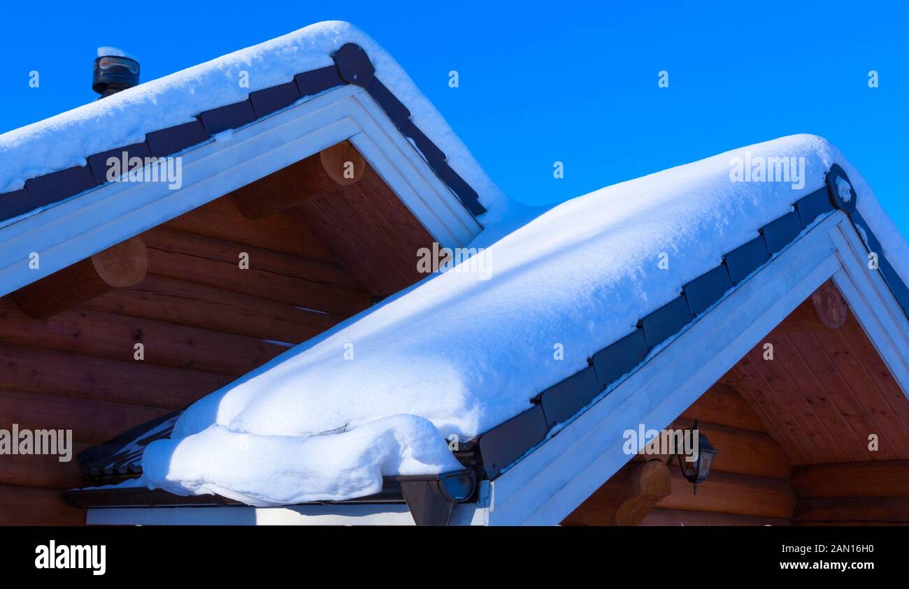Snow drift on roof after of snowfalls on sunny day. Wooden house in the ...