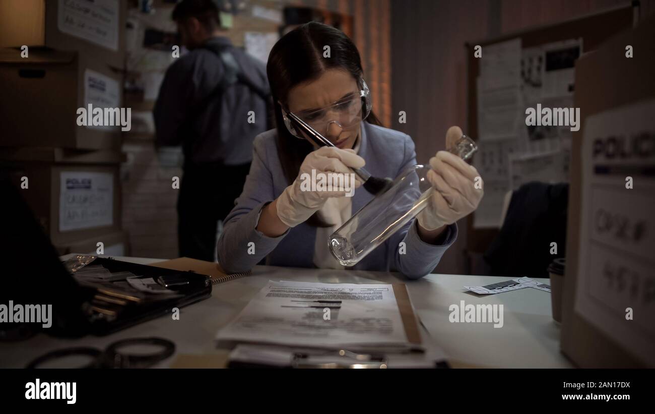 Qualified female officer taking the fingerprints from evidence glass ...