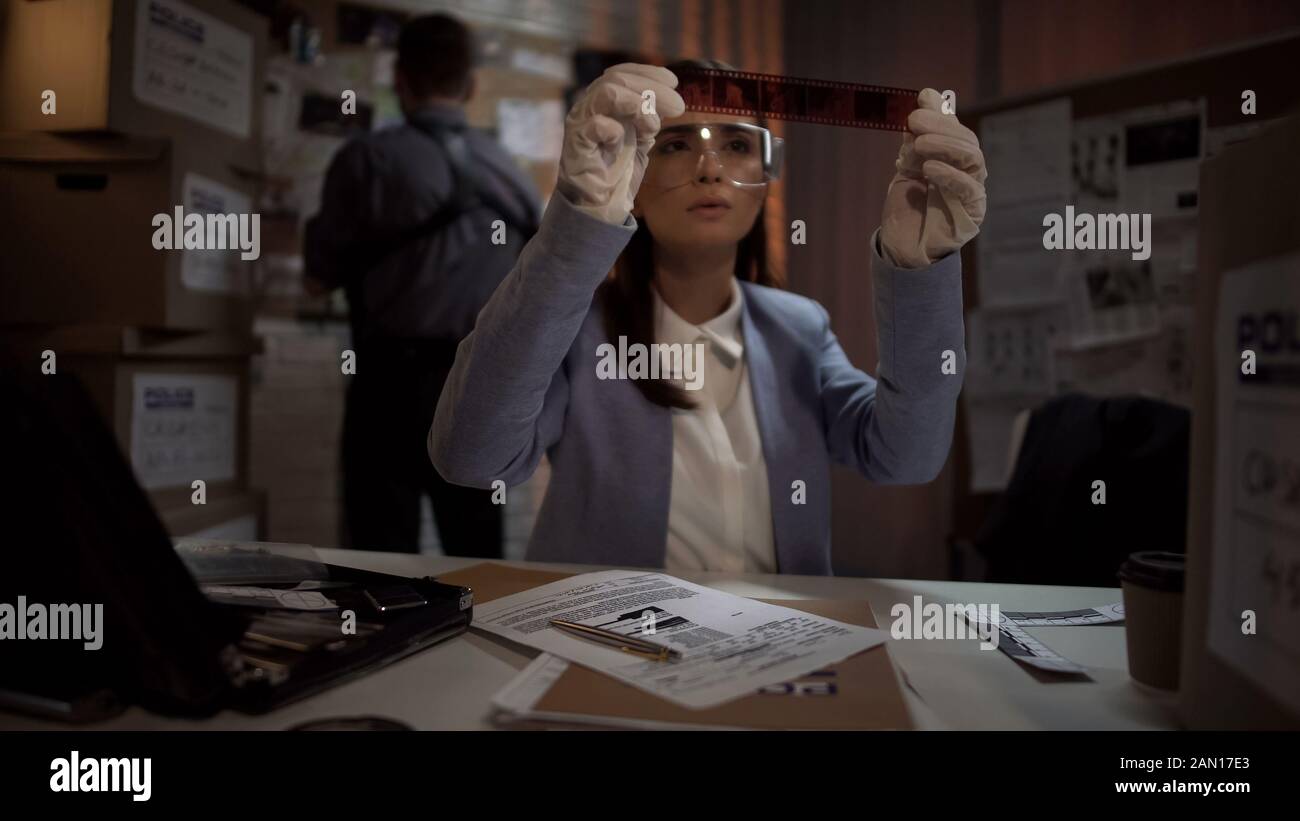 Police scientist looking at criminal scene photos, searching for clues ...