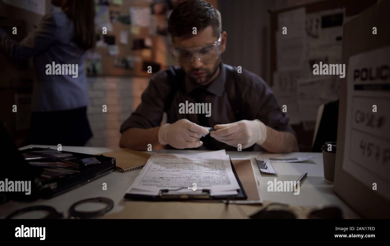 Forensic scientist male examining the evidence bullet from the crime ...