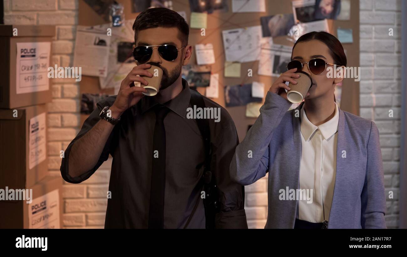 Cool professional detectives in eyeglasses drinking coffee, private ...