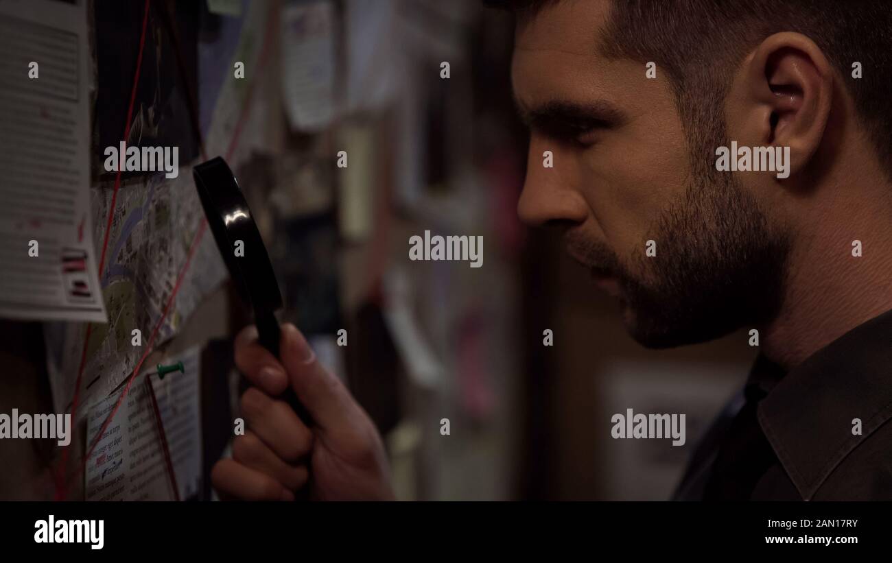 Serious policeman searching for location on city map with magnifying ...