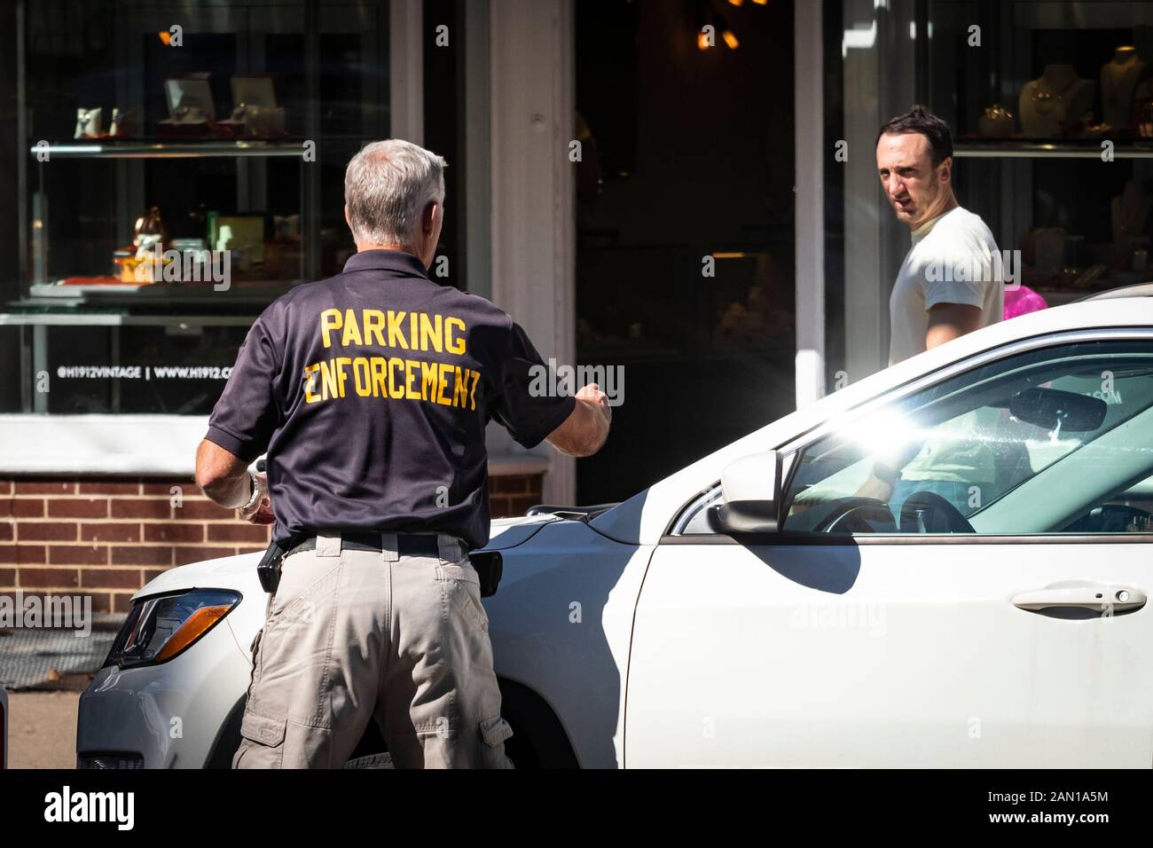 Parking Enforcement man places citation ticket on car - while man gives ...