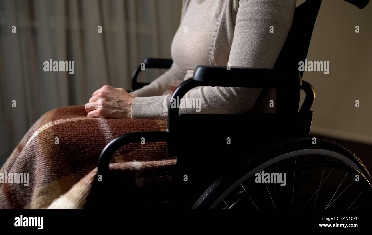 Invalid woman moving in wheelchair at home for elderly, charity ...