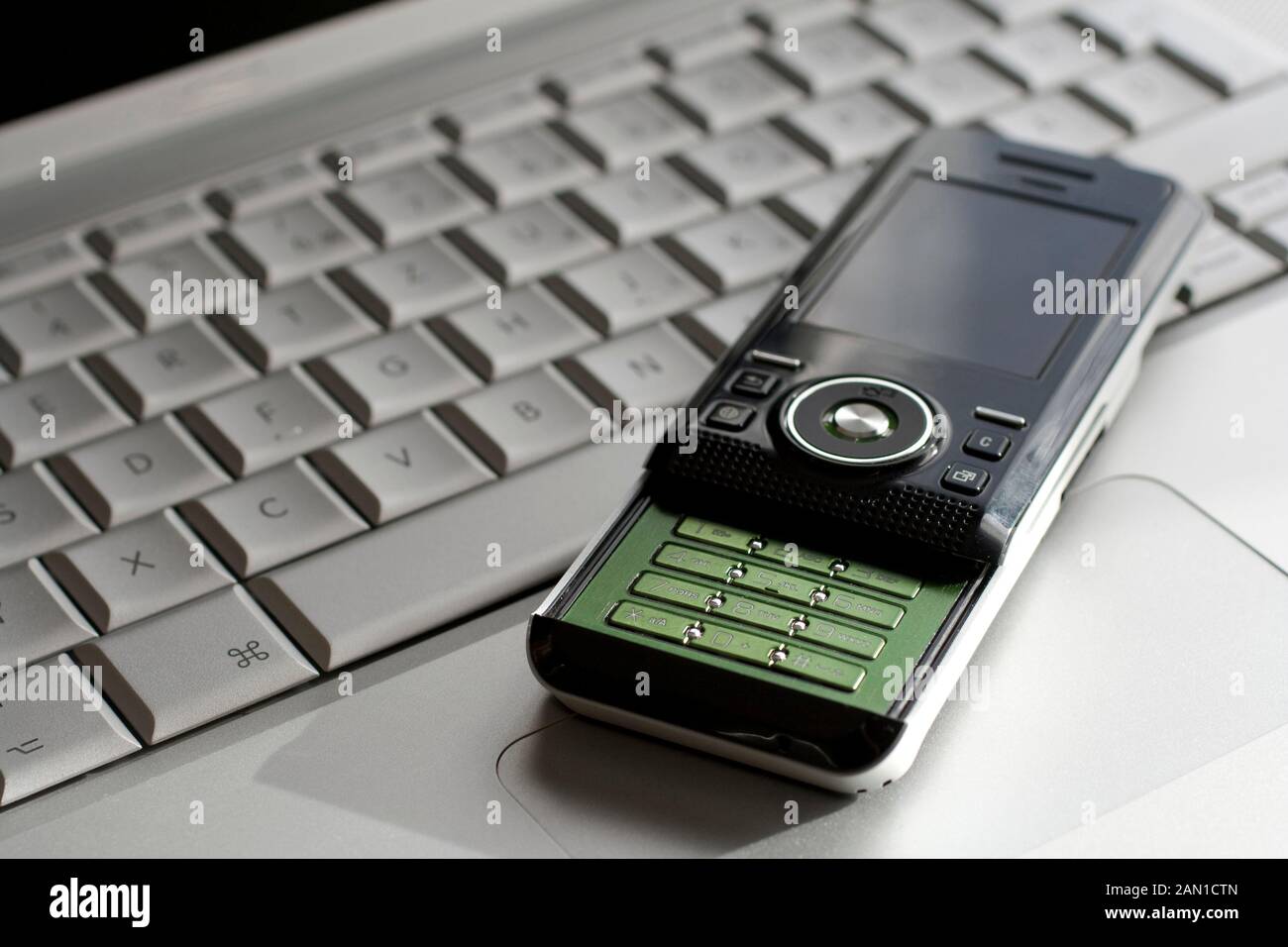 Old mobile phone (slider) on a silver laptop Stock Photo - Alamy