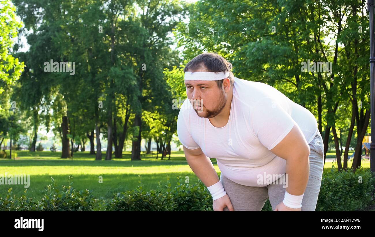 Obese man running outdoors, out of breath, overcoming laziness and ...