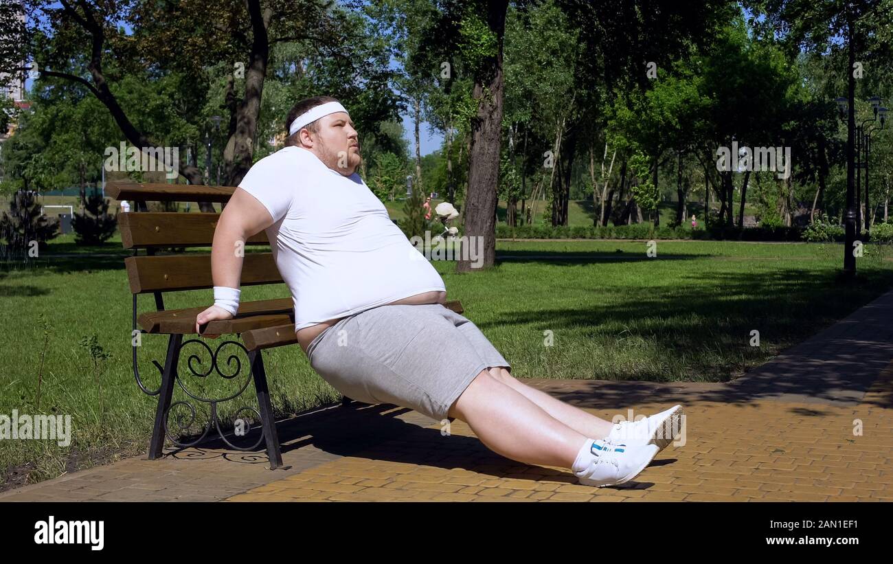 Obese young man exercising on bench, outdoor workouts, struggle to slim ...
