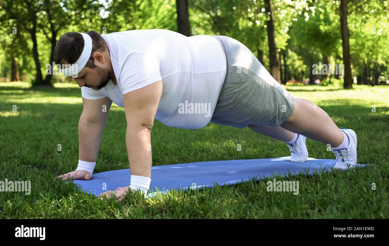 Fat man doing plank, training outdoors, desire to be slim, motivation ...