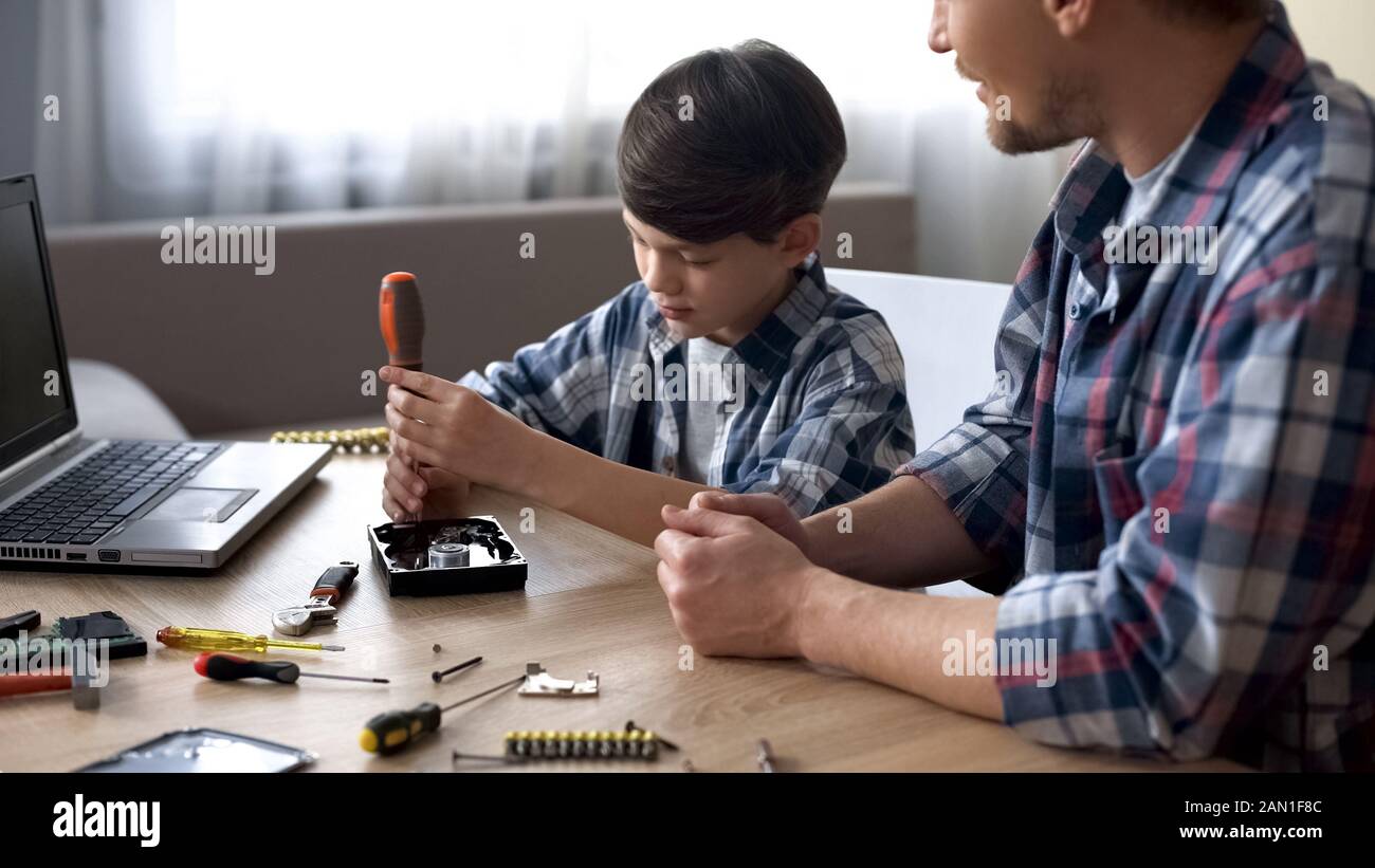 Father teaching his cute little son to repair hard disk drive at home ...