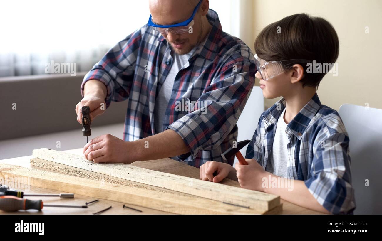 Dad teaching little son how to use hammer safely, family leisure, hobby ...