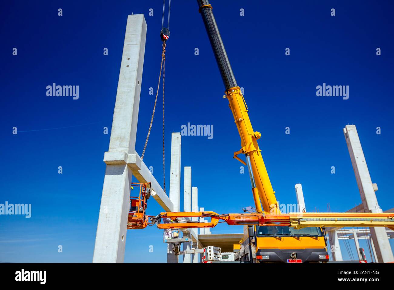 Mobile crane is operating and worker is assembly concrete joist in high ...