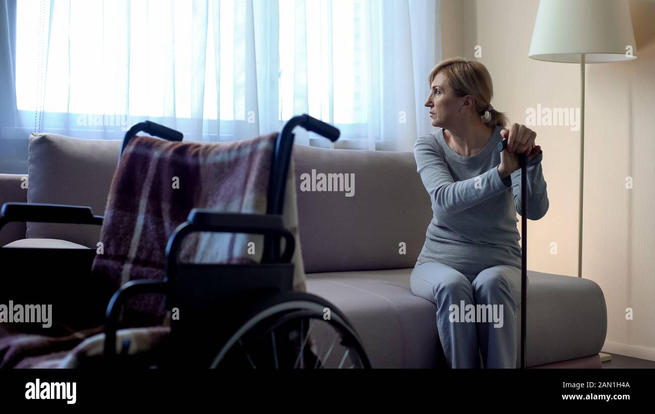 Sad retired lady waiting for husband at hospital, looking in window ...