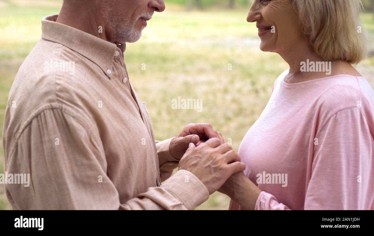 Handsome retired man covering female hands, romantic date in park ...