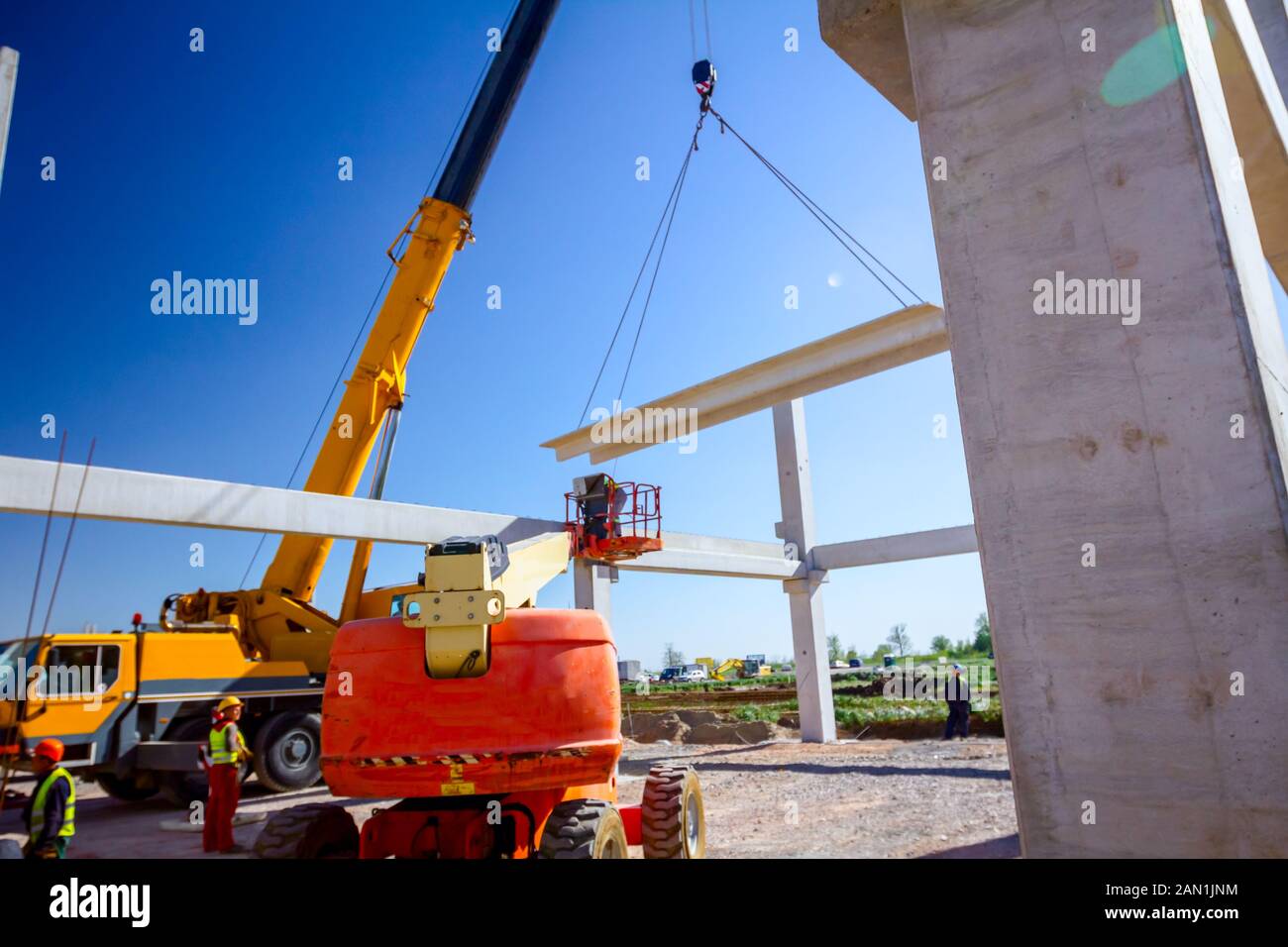 Mobile crane is operating and worker is assembly concrete joist in high ...