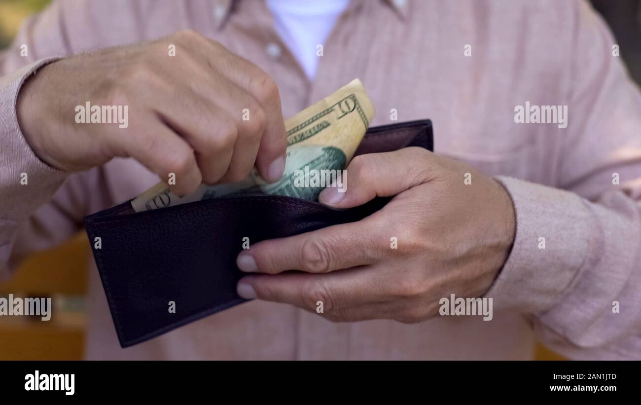 Poor pensioner putting dollar banknote in empty wallet, low retirement ...